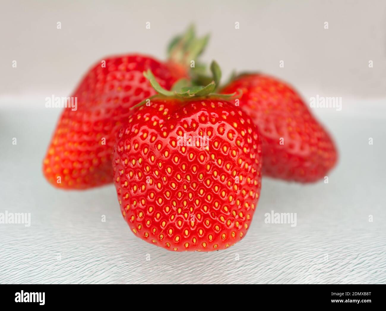 Three strawberries on white background Stock Photo - Alamy