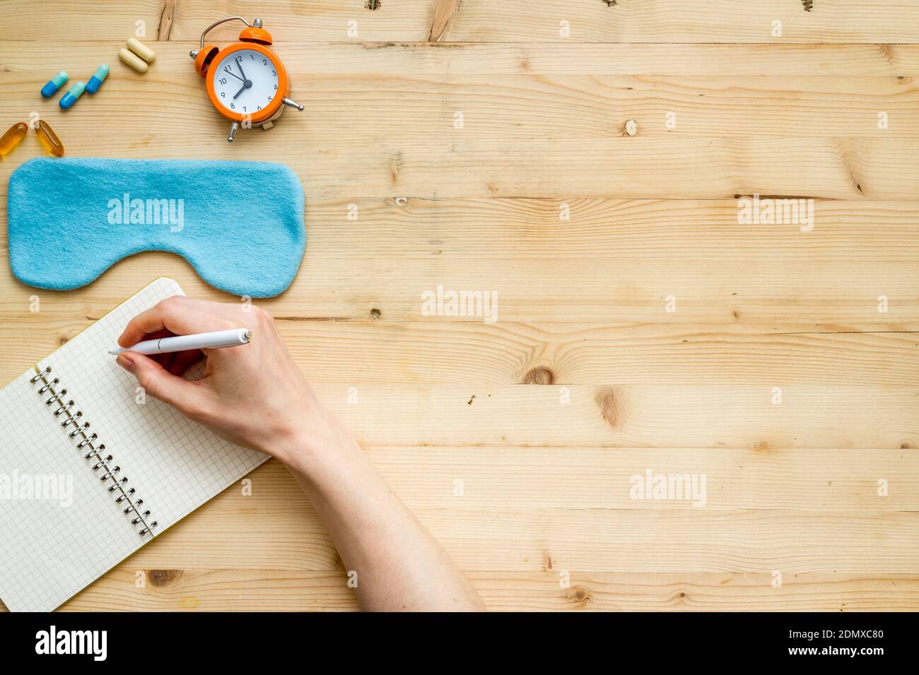 Female hand write in notebook - day plan before sleeping. Top view ...