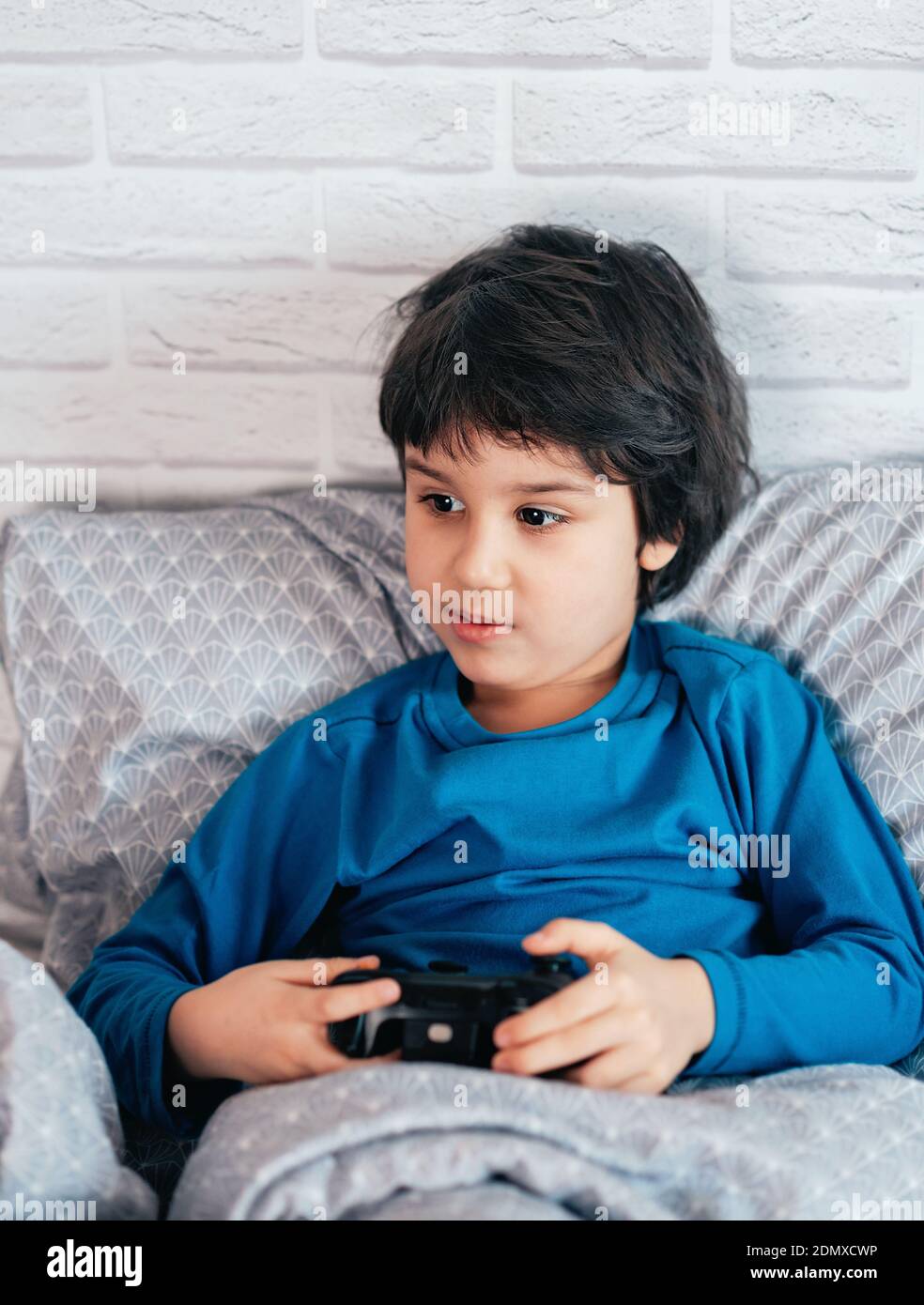 Close up of child hands playing video game at home. kid in bed wih ...