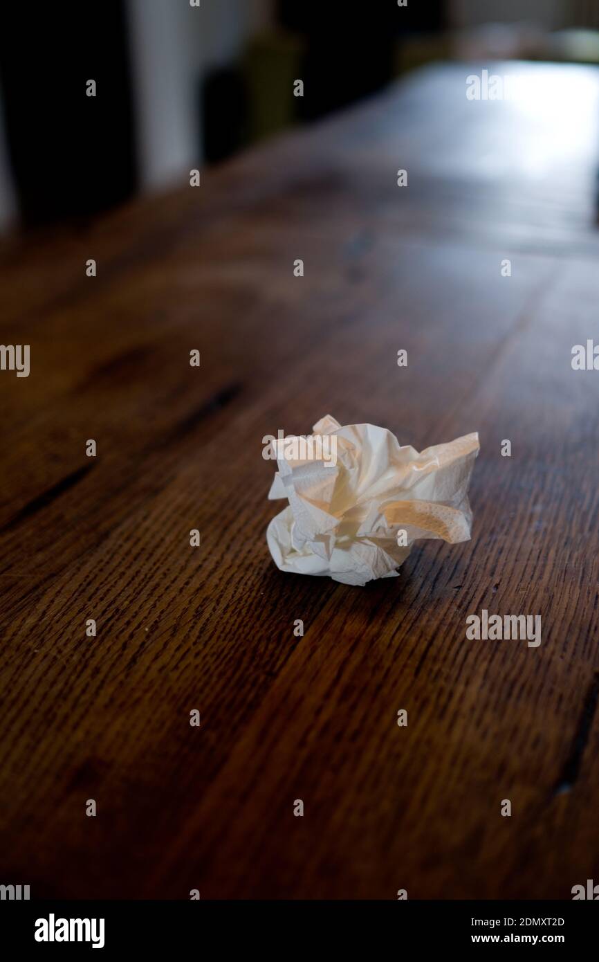 a single used and screwed up white paper tissue left on an empty wooden ...
