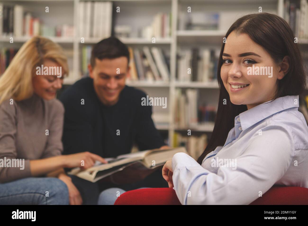 Lovely happy female student smiling to the camera, sitting relaxed at ...