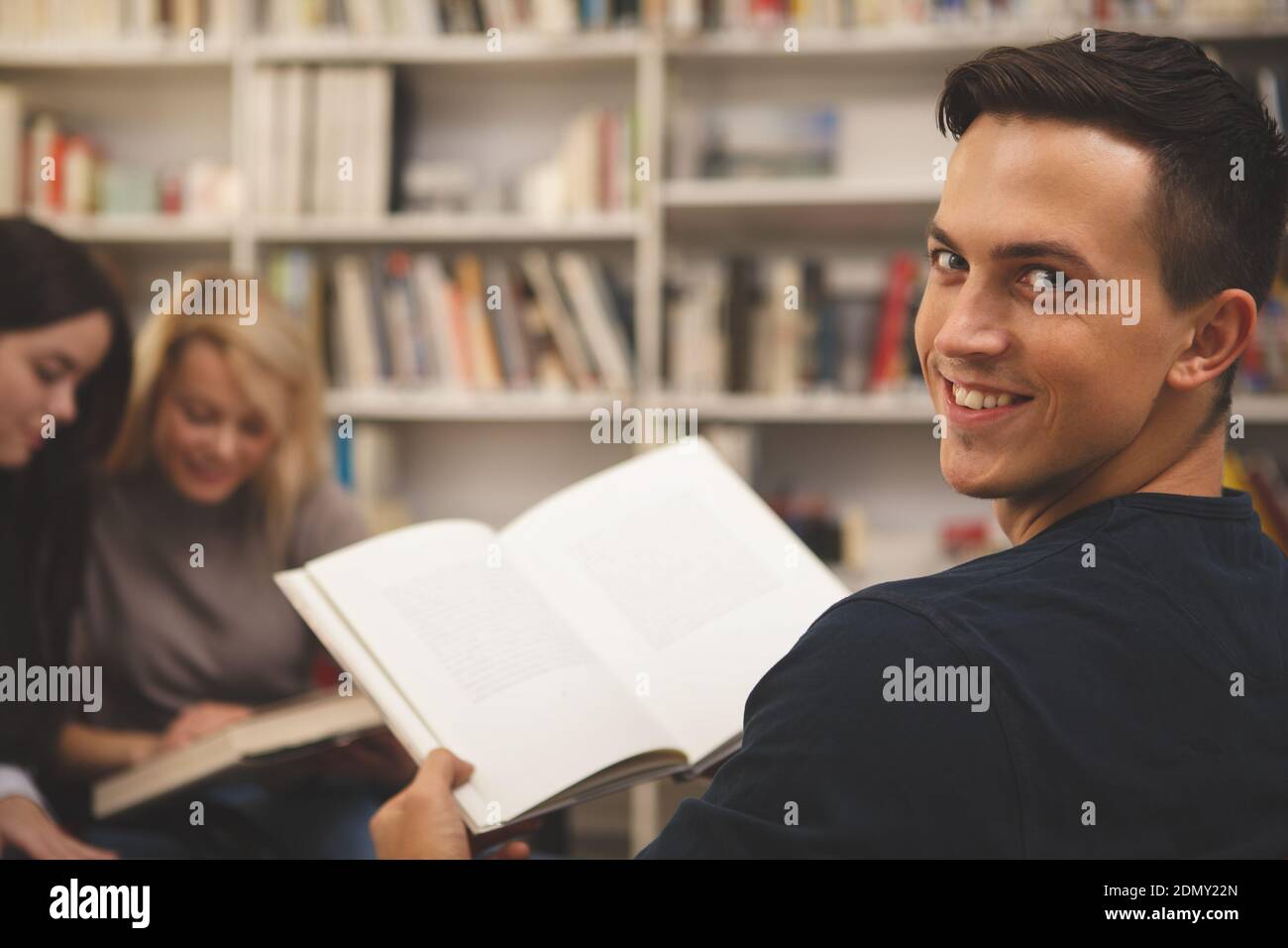 Handsome happy male studenta smiling to the camera over his shoulder ...