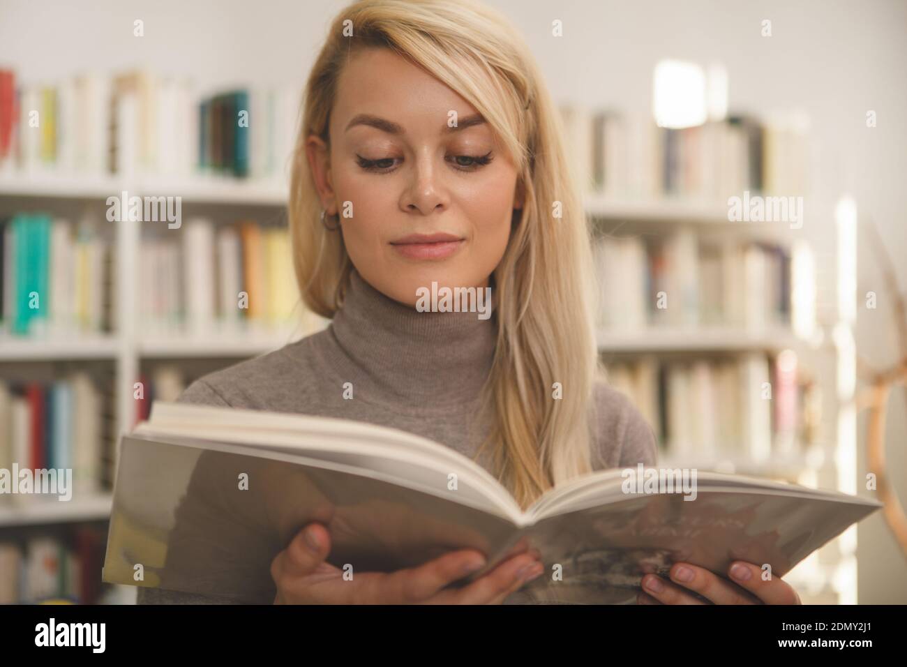 Low angle shot of a beautiful long haired young woman smiling, reading ...