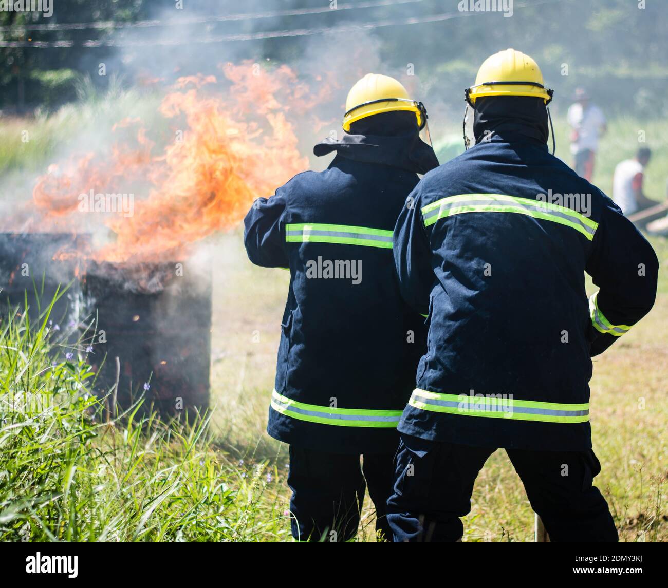 Rear View Of Firefighters Standing Against Fire On Field Stock Photo ...