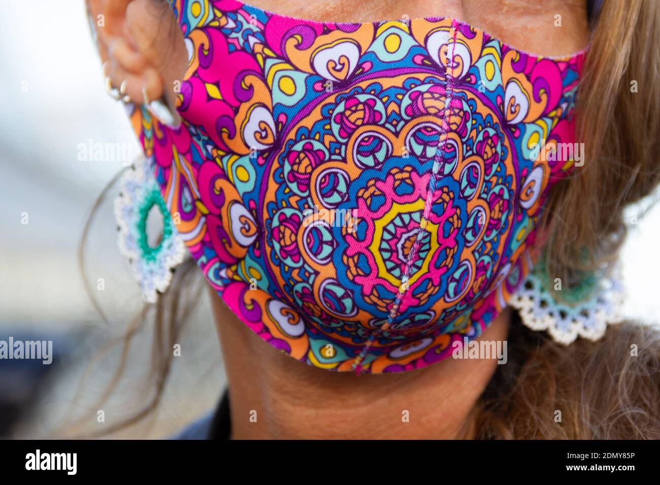 Colorful face mask with mandala pattern worn by woman. Covid-19 ...