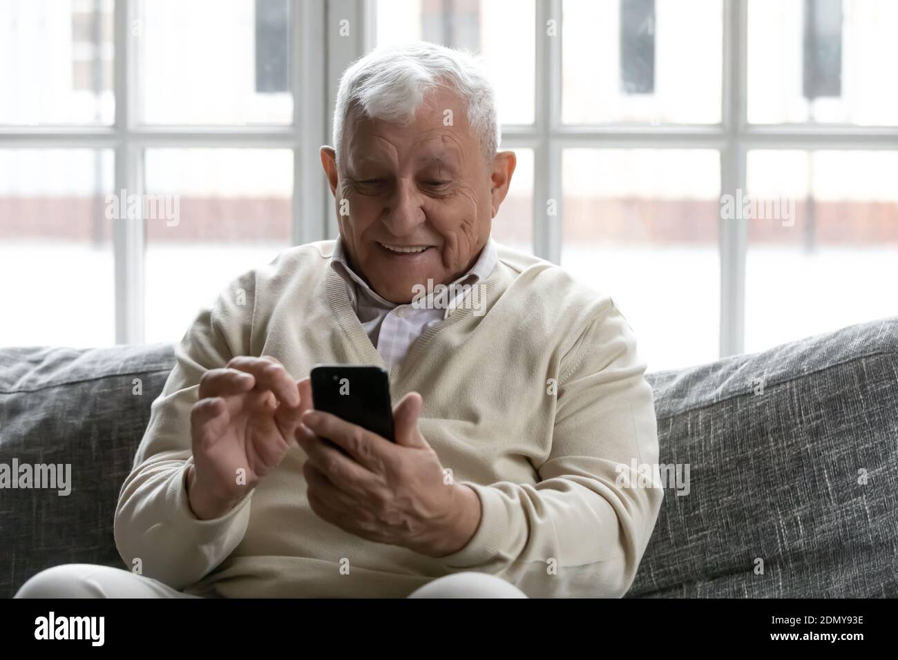 Happy active elderly male using modern phone exploring gadget functions ...