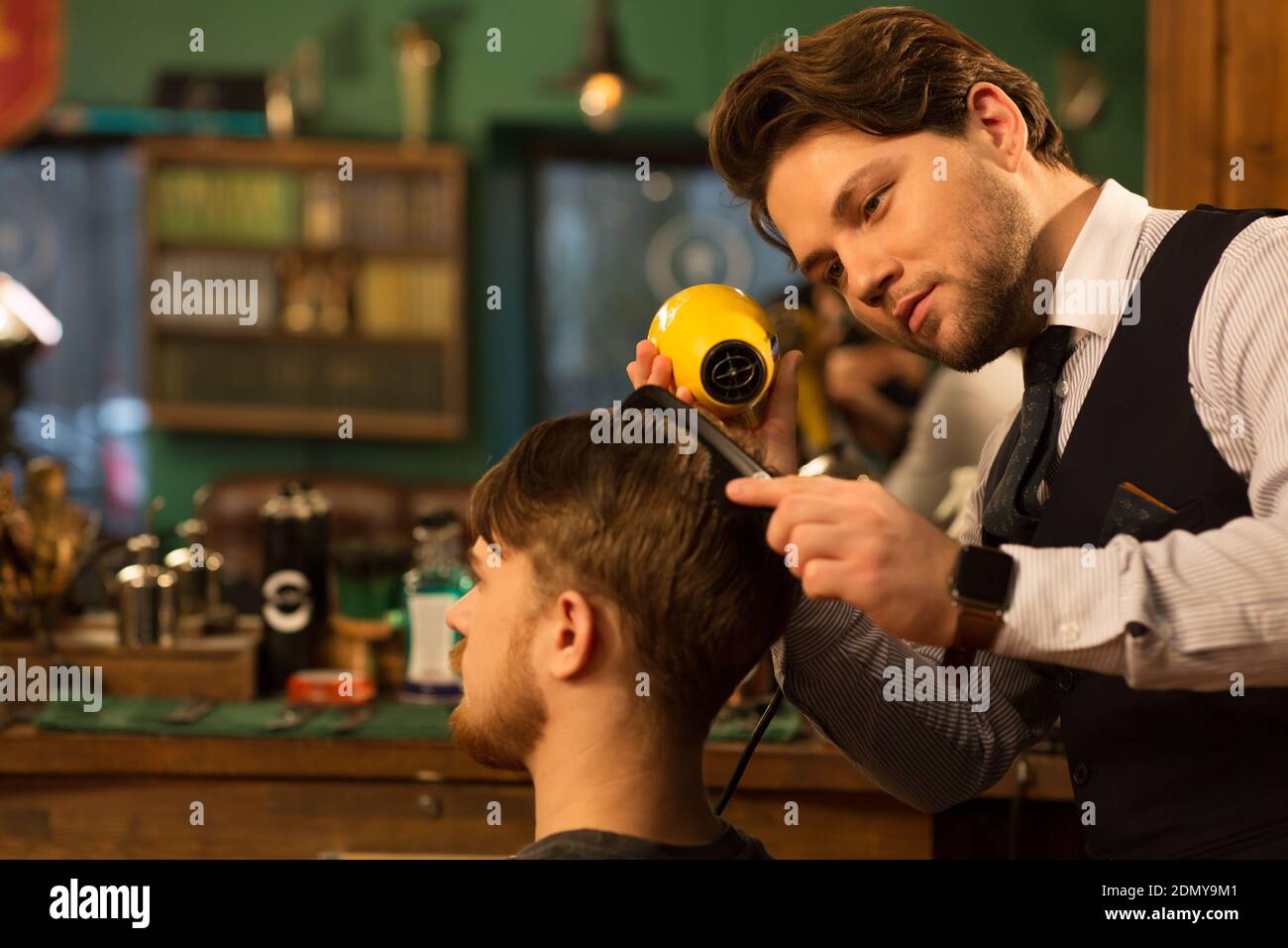 Handsome bearded professional barber working at his barbershop drying ...