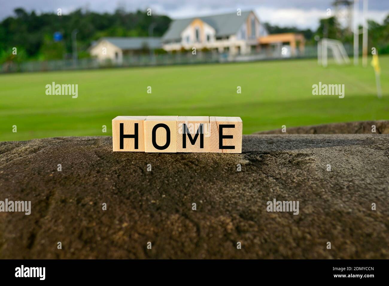 Home number on wooden block on top of big stone with house background ...