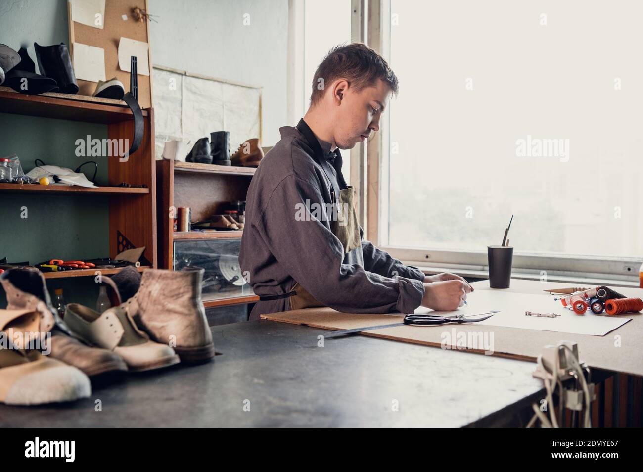 An experienced shoemaker in a shoe production workshop makes a pattern ...