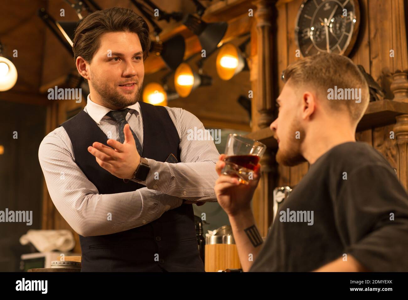 Handsome cheerful professional barber talking to his client after ...