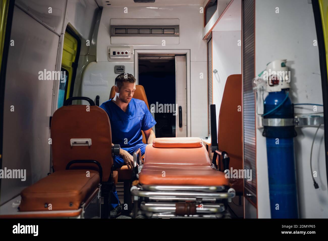 Paramedic in a uniform sitting in the ambulance car Stock Photo - Alamy