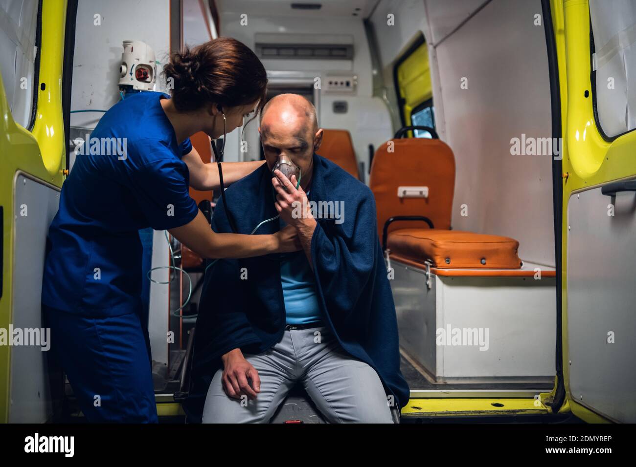A paramedic examining a man rescued from the fire in an ambulance car ...