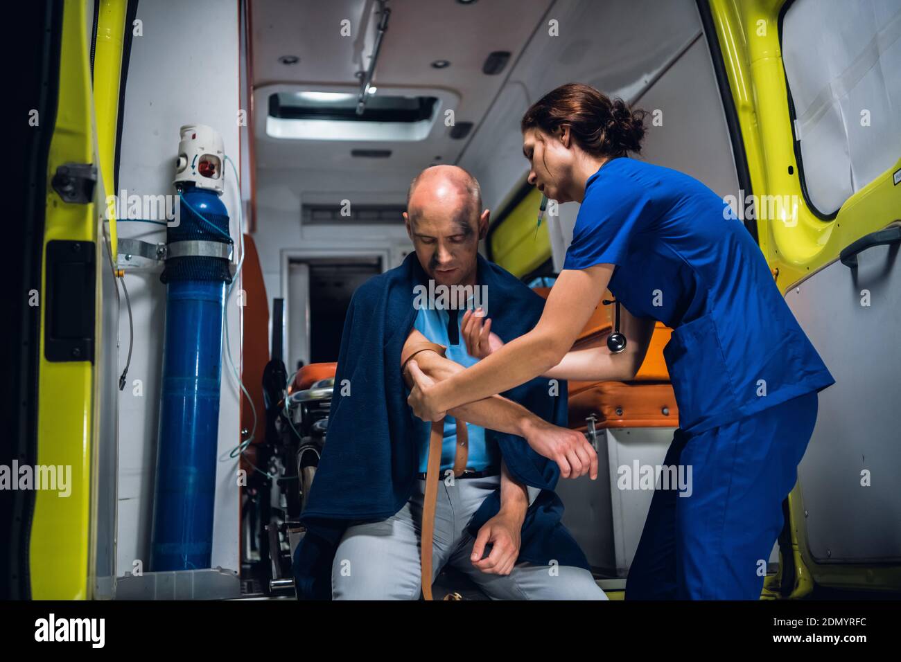 Young nurse wraps a tourniquet around a hand of her patient in an ...
