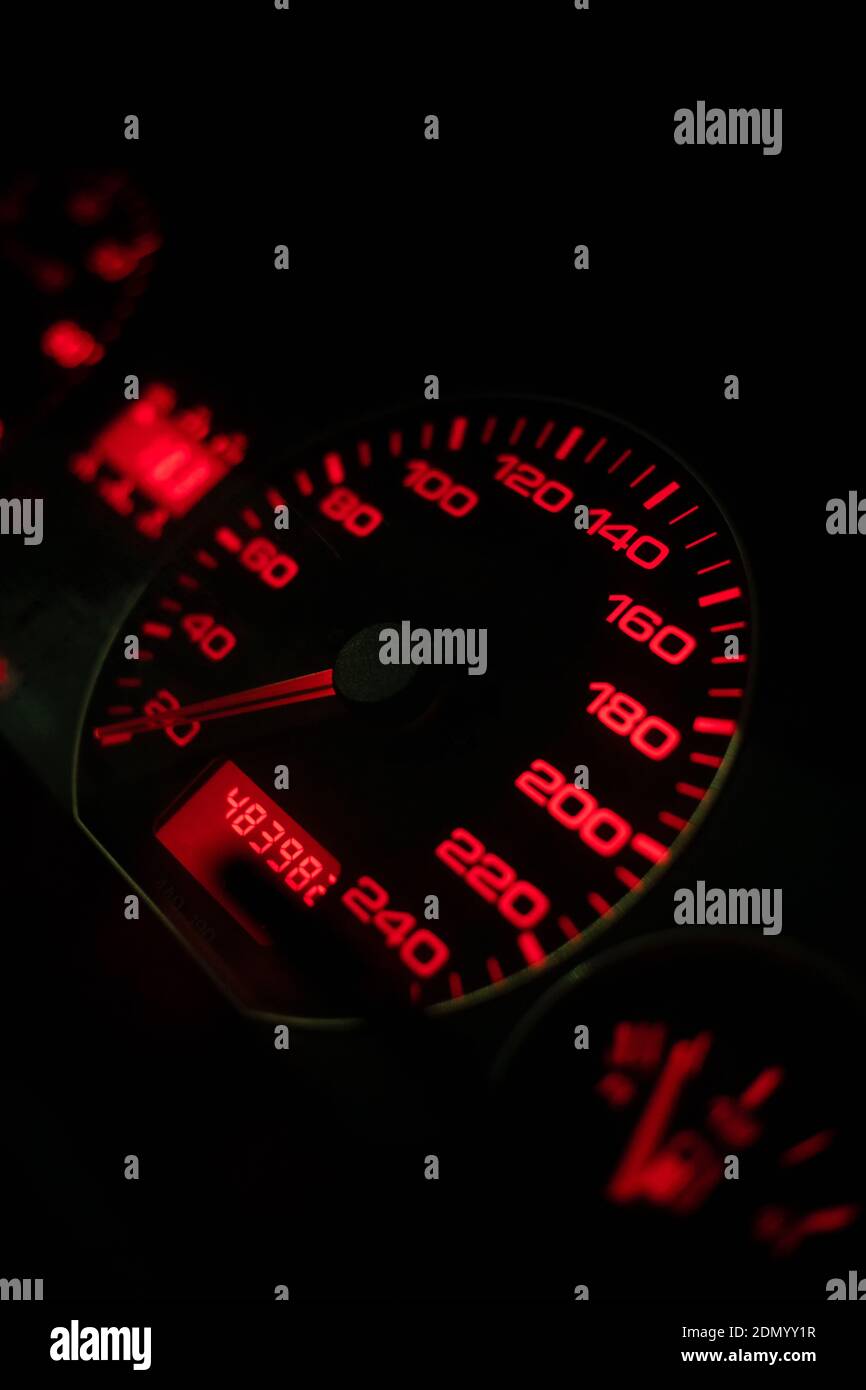 Speedometer with red light at night close-up. Car dashboard. Vertical ...