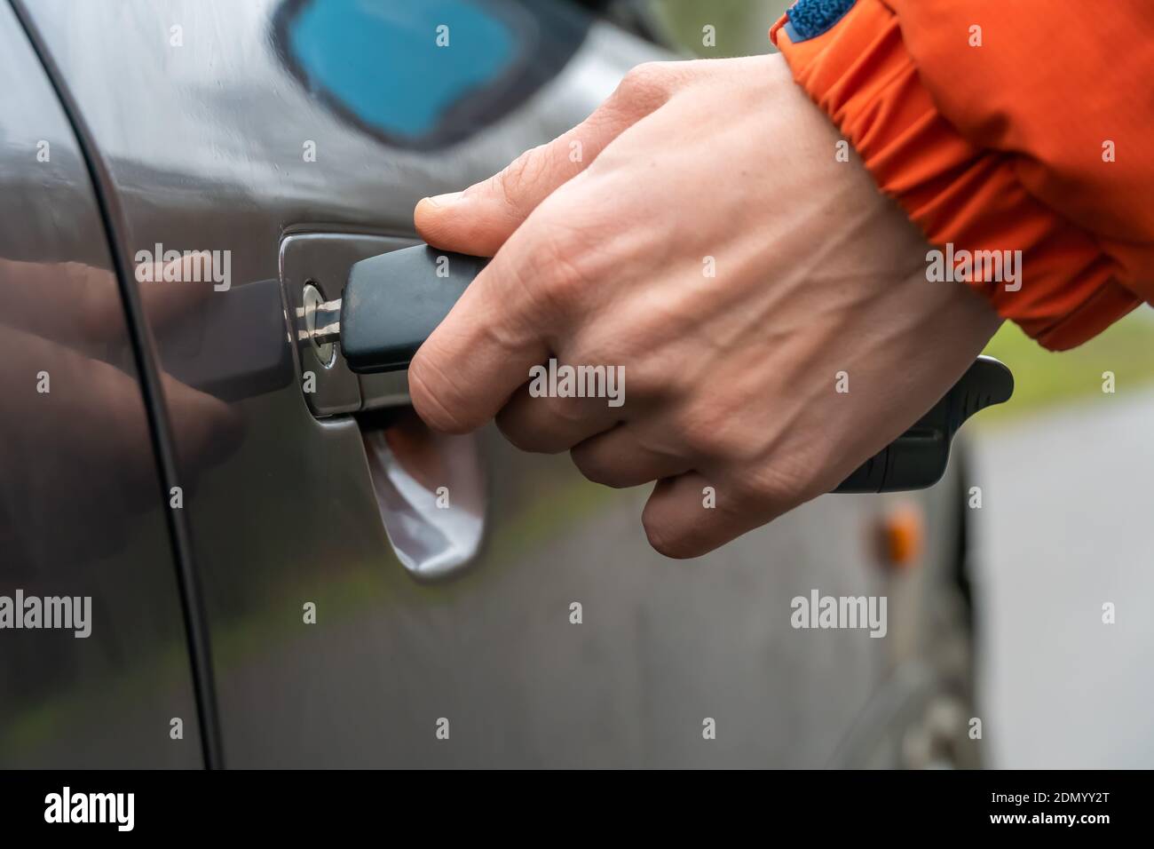 Close-up of a man's left hand in an orange jacket inserting a key into ...