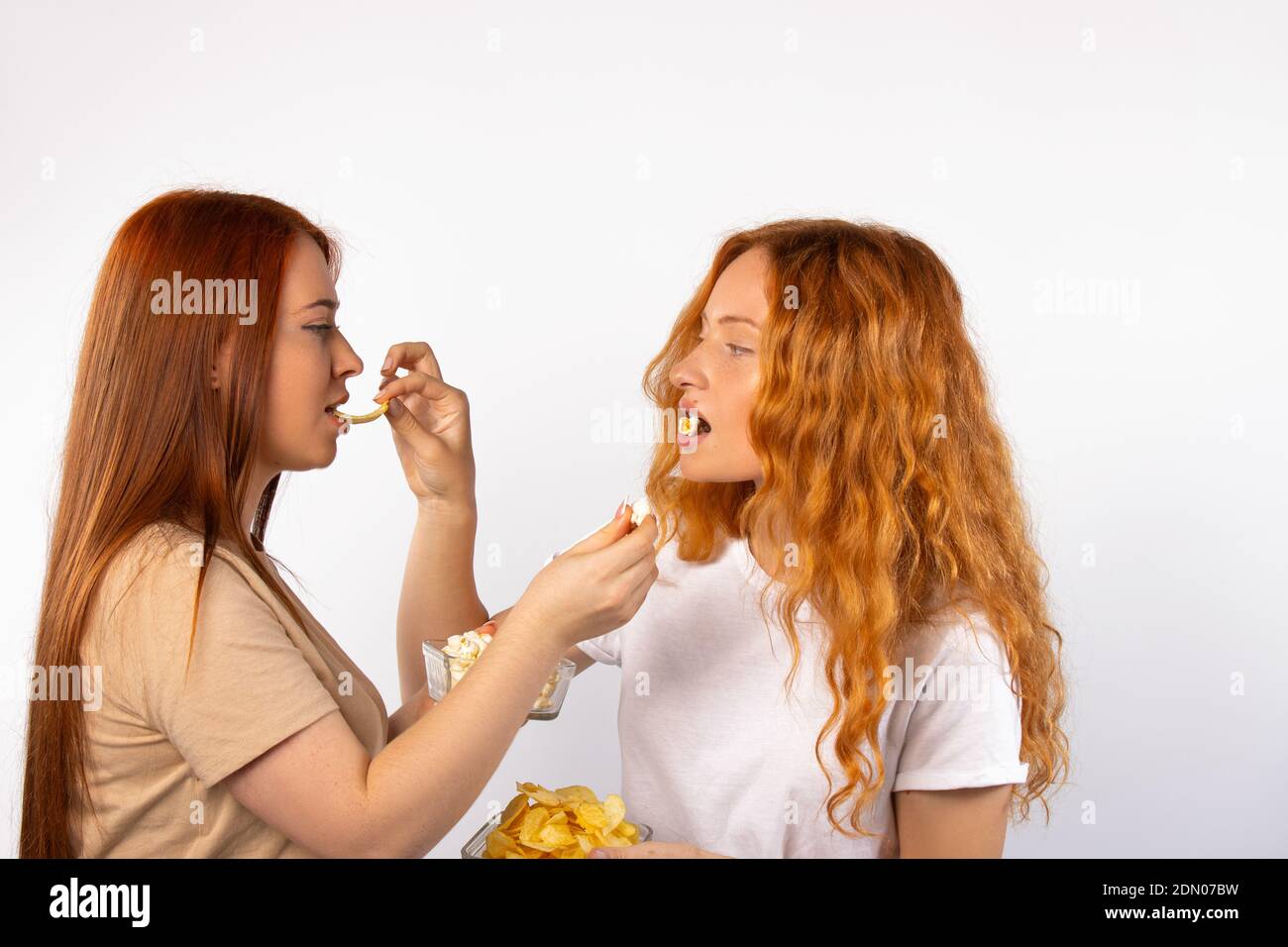 Best friends on a white background feed each other with popcorn and ...