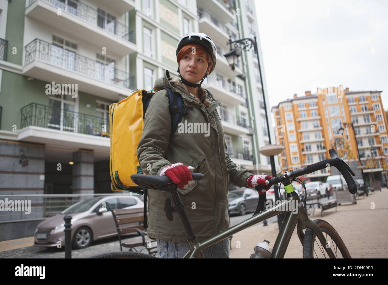 Low angle shot of a female delivery courier walking with her bicycle on ...