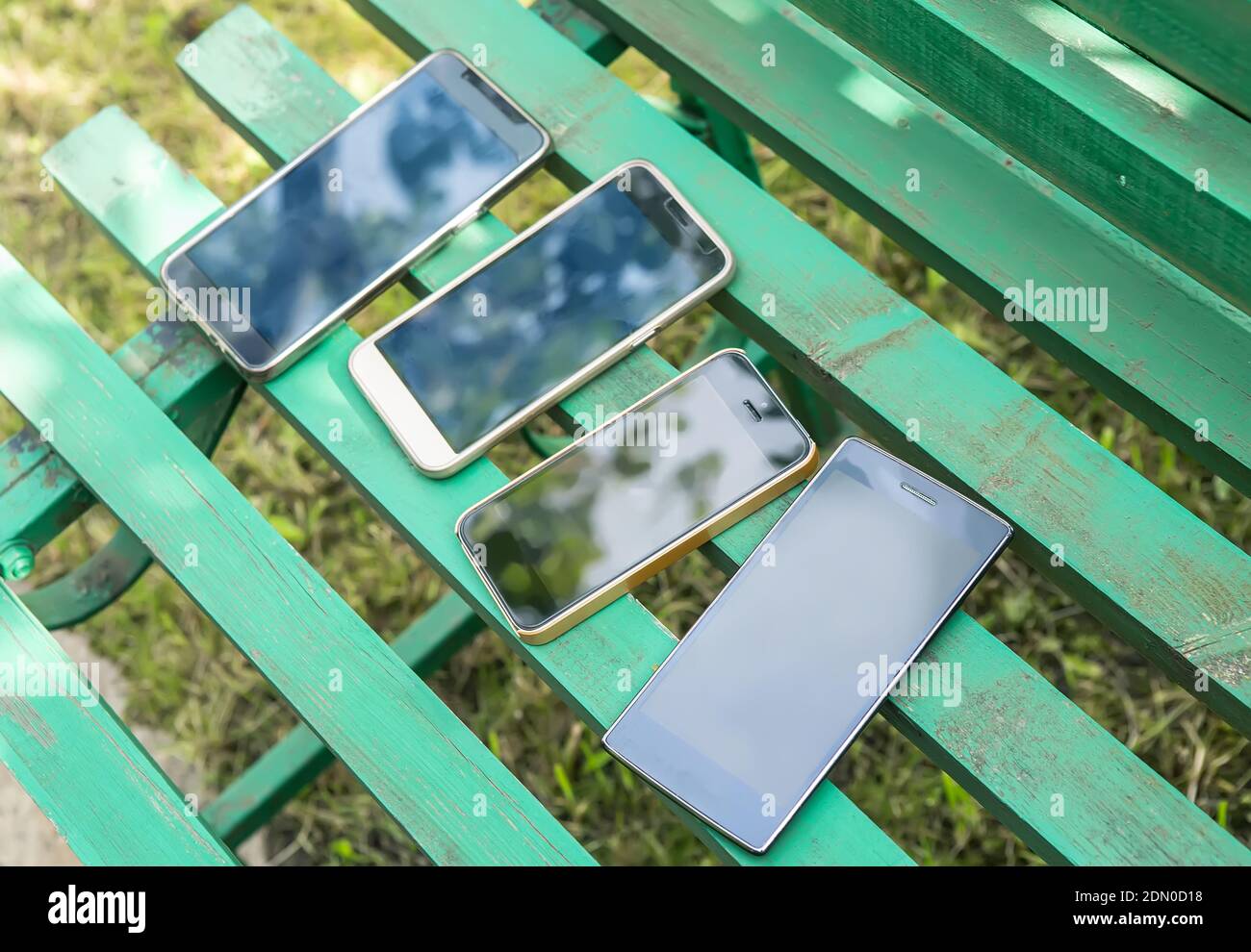 four modern smartphones on a bench in summer Stock Photo - Alamy