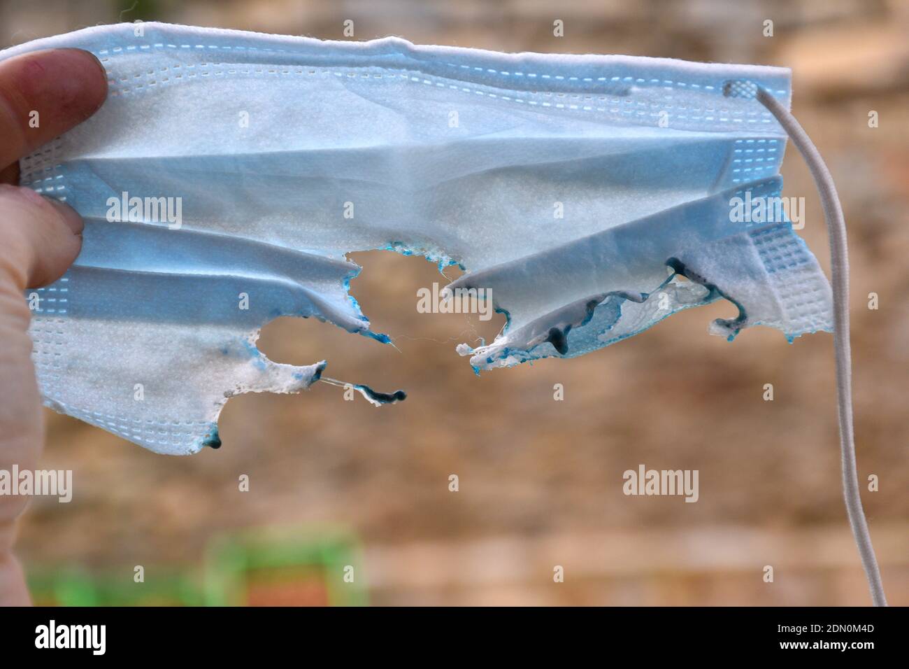 Burned blue surgical mask held by hand Stock Photo - Alamy