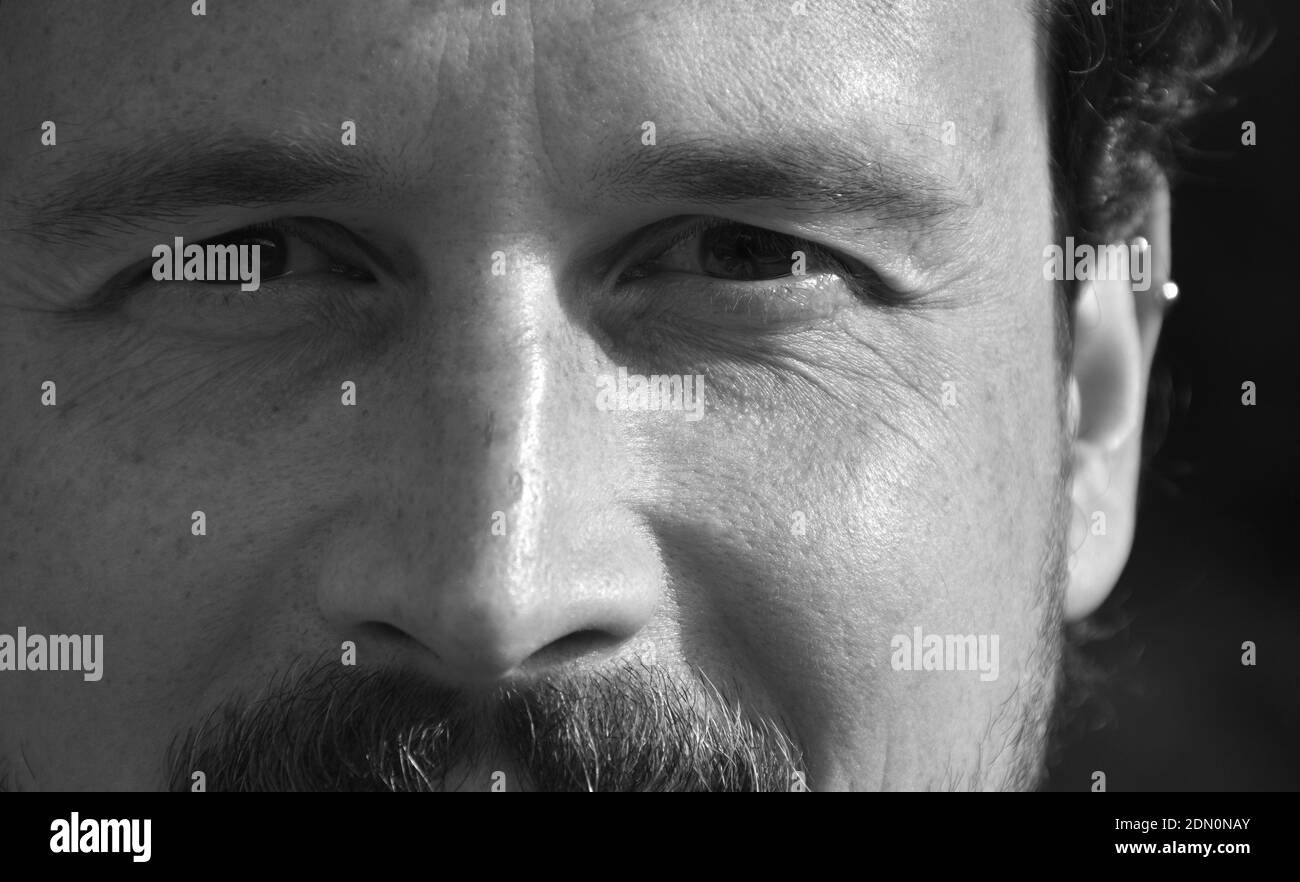 Close-up of man with moustache smiling, age marks on skin. Black and ...