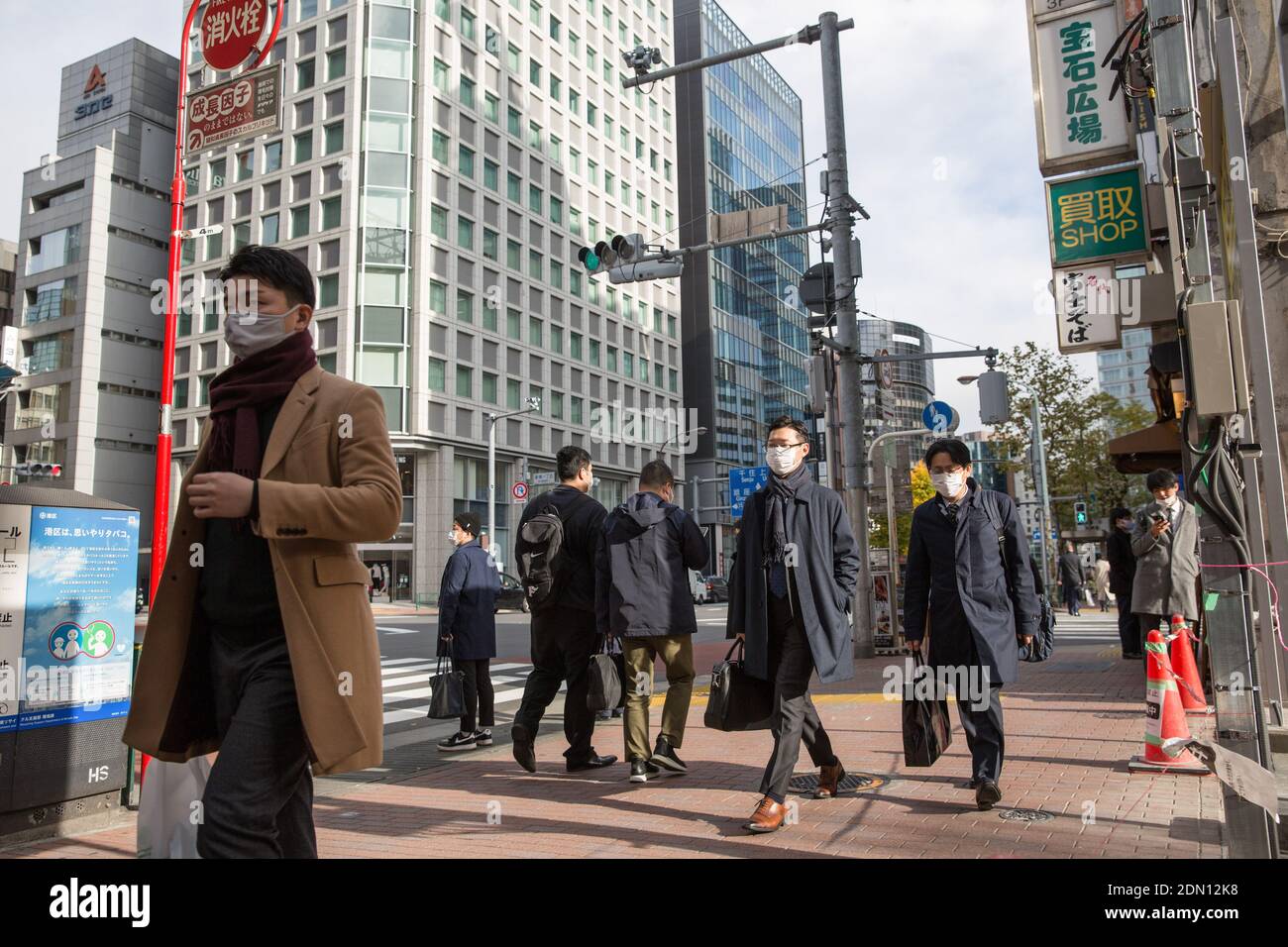 People wearing masks walk along Streets of Shinbashi district in Tokyo ...