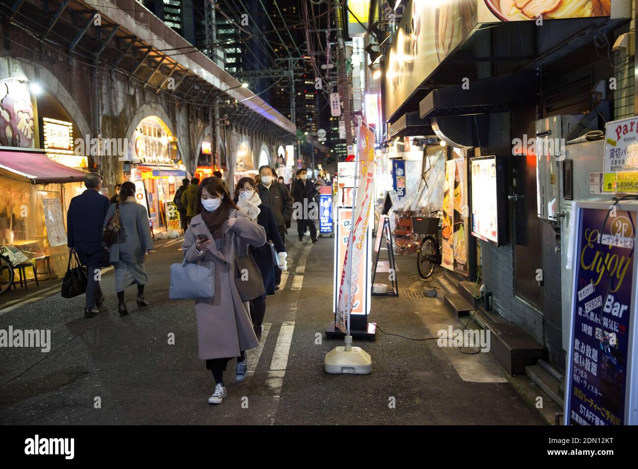 Women wearing masks walk towards Shinbashi train station entrance in ...