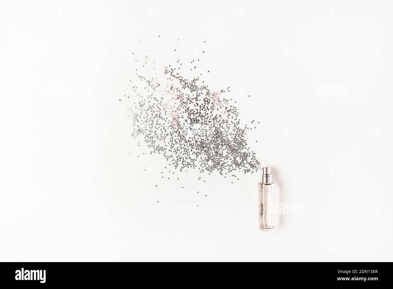 Stylish bottle of perfume with spray of silver star shaped sparkles on ...