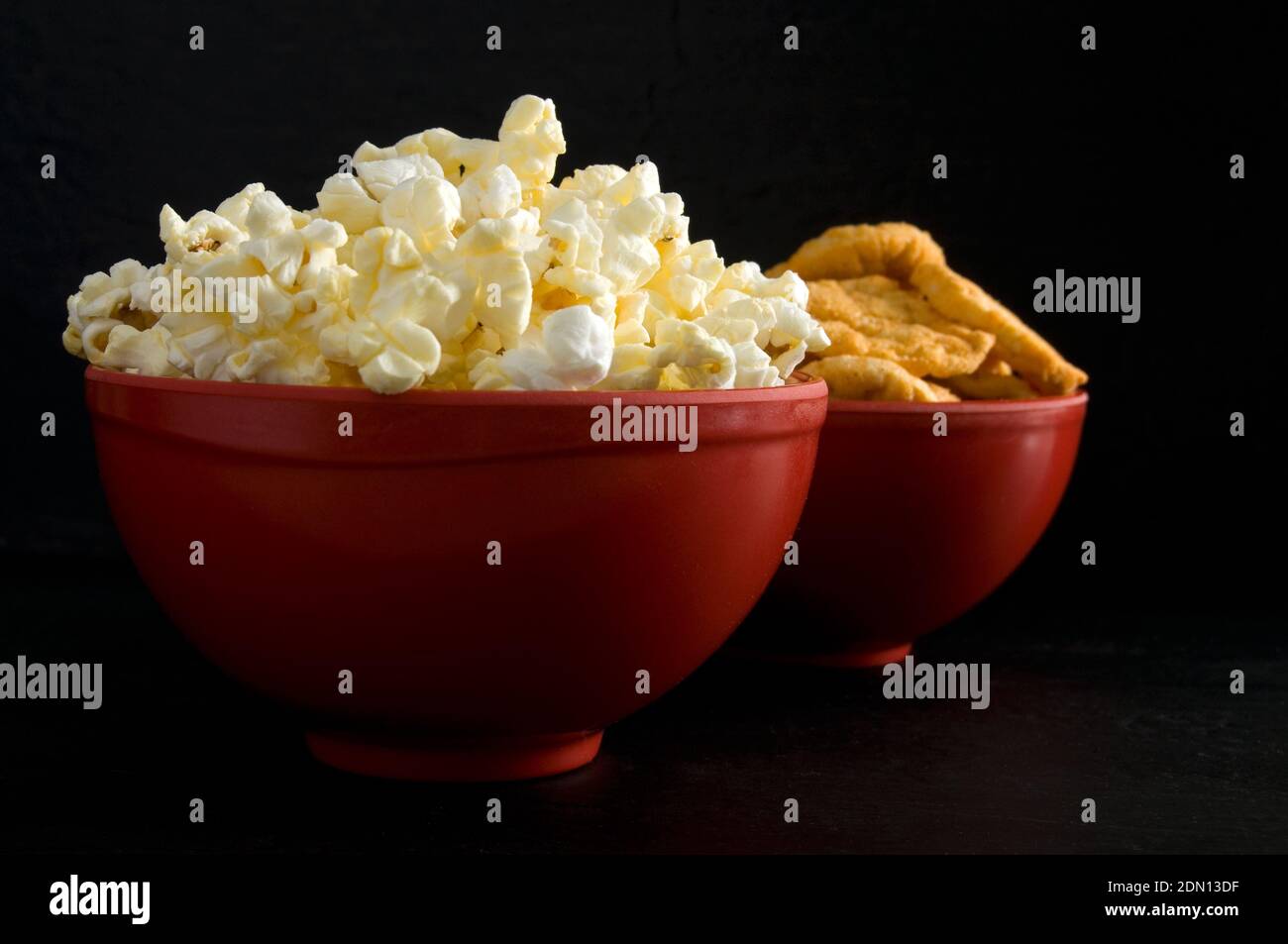 Close Side View of Buttered Popcorn and BBQ Rice Chips in Red Bowls ...