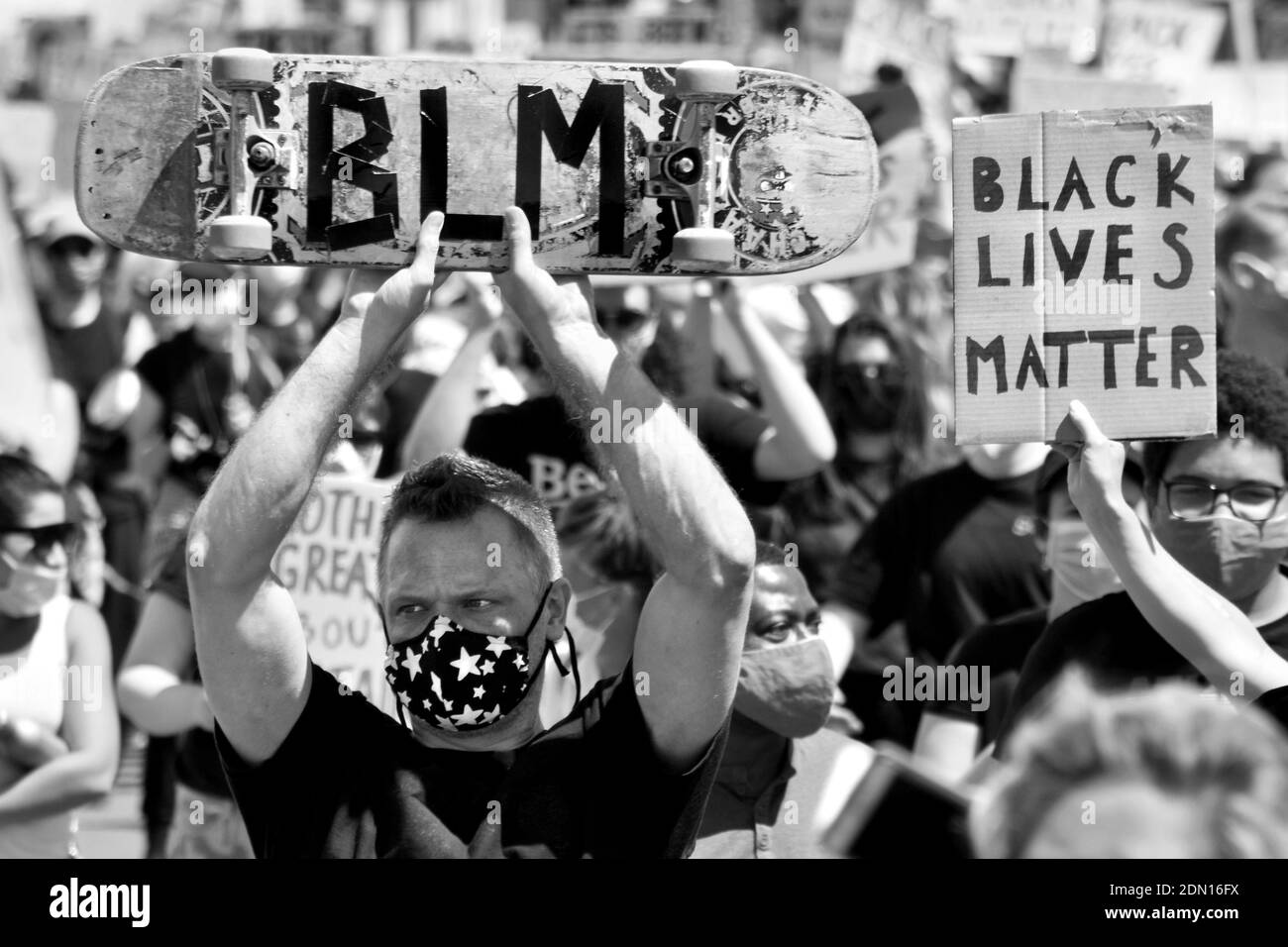 Black Lives Matter in black and white - man with face covering holding ...