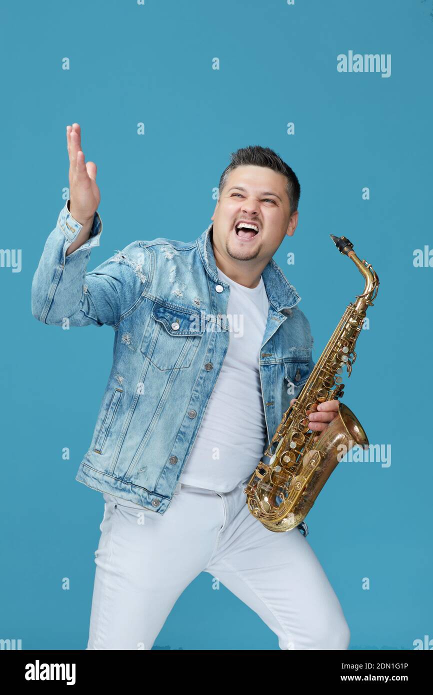 happy musician man with the saxophone on blue studio background. Music ...