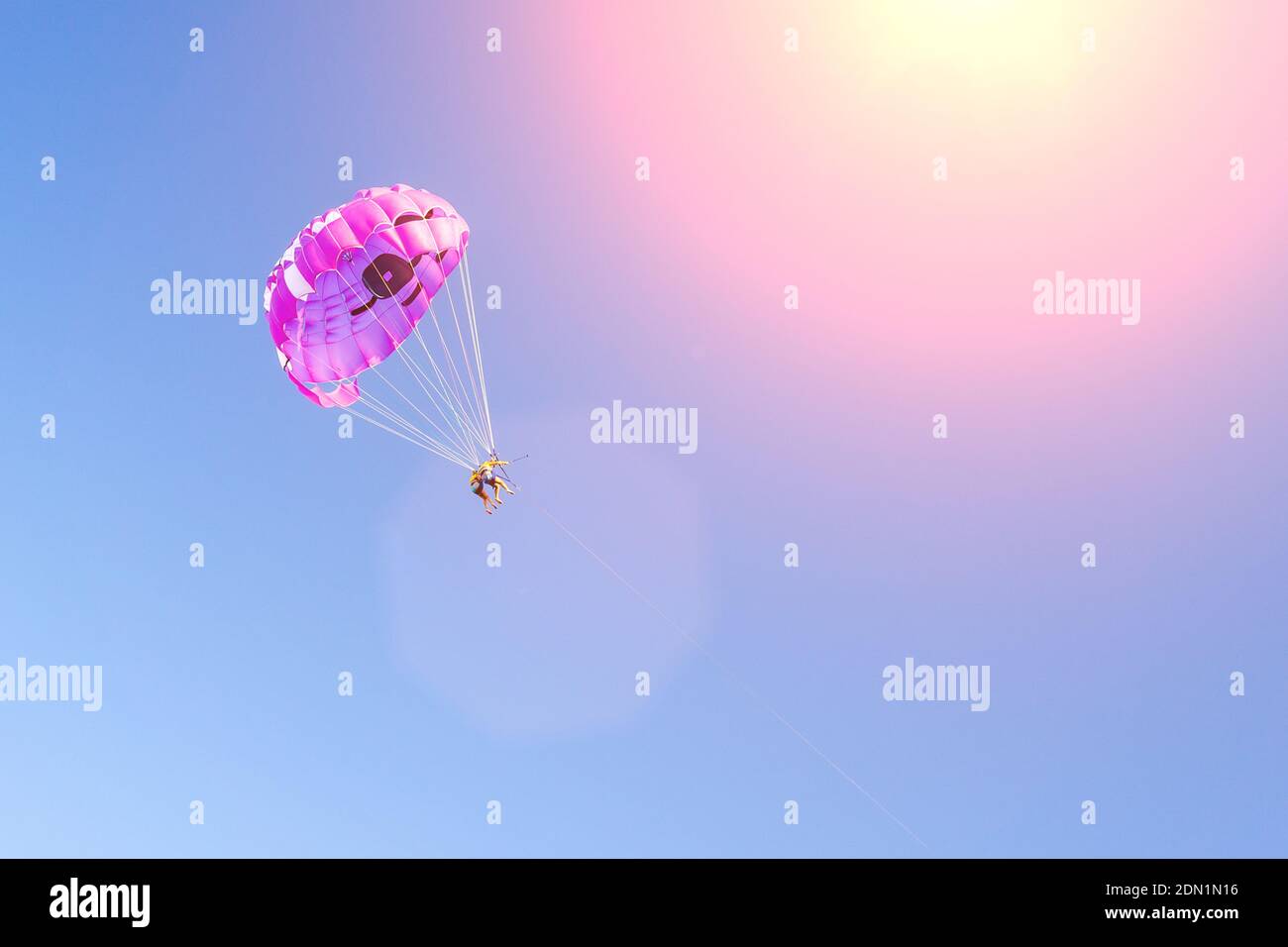 parasailing people under a parachute hanging in the air in summer. fun ...