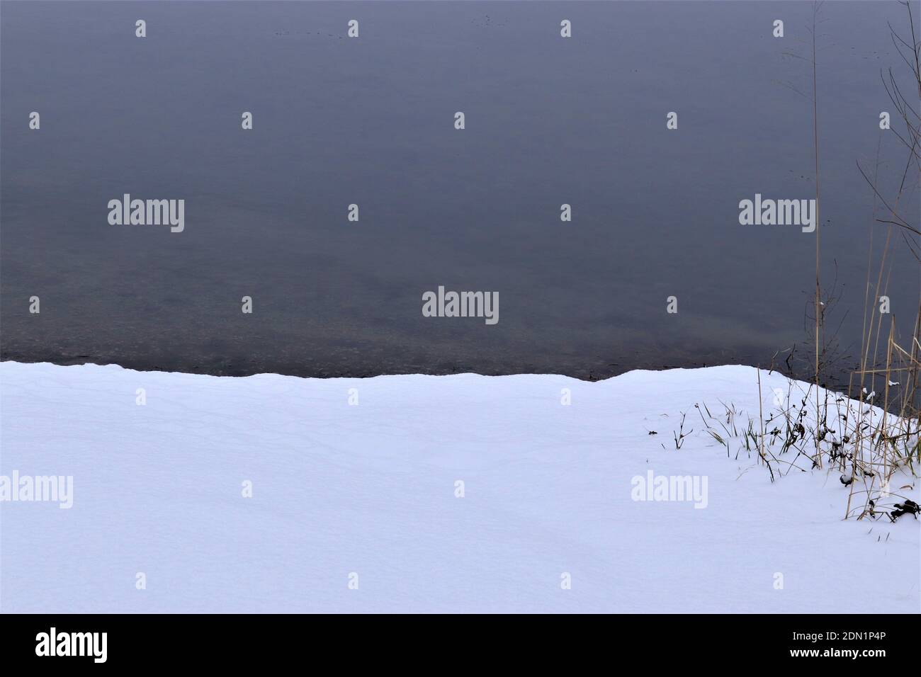 The lake shore is covered with snow. Snow and water. A clear boundary ...