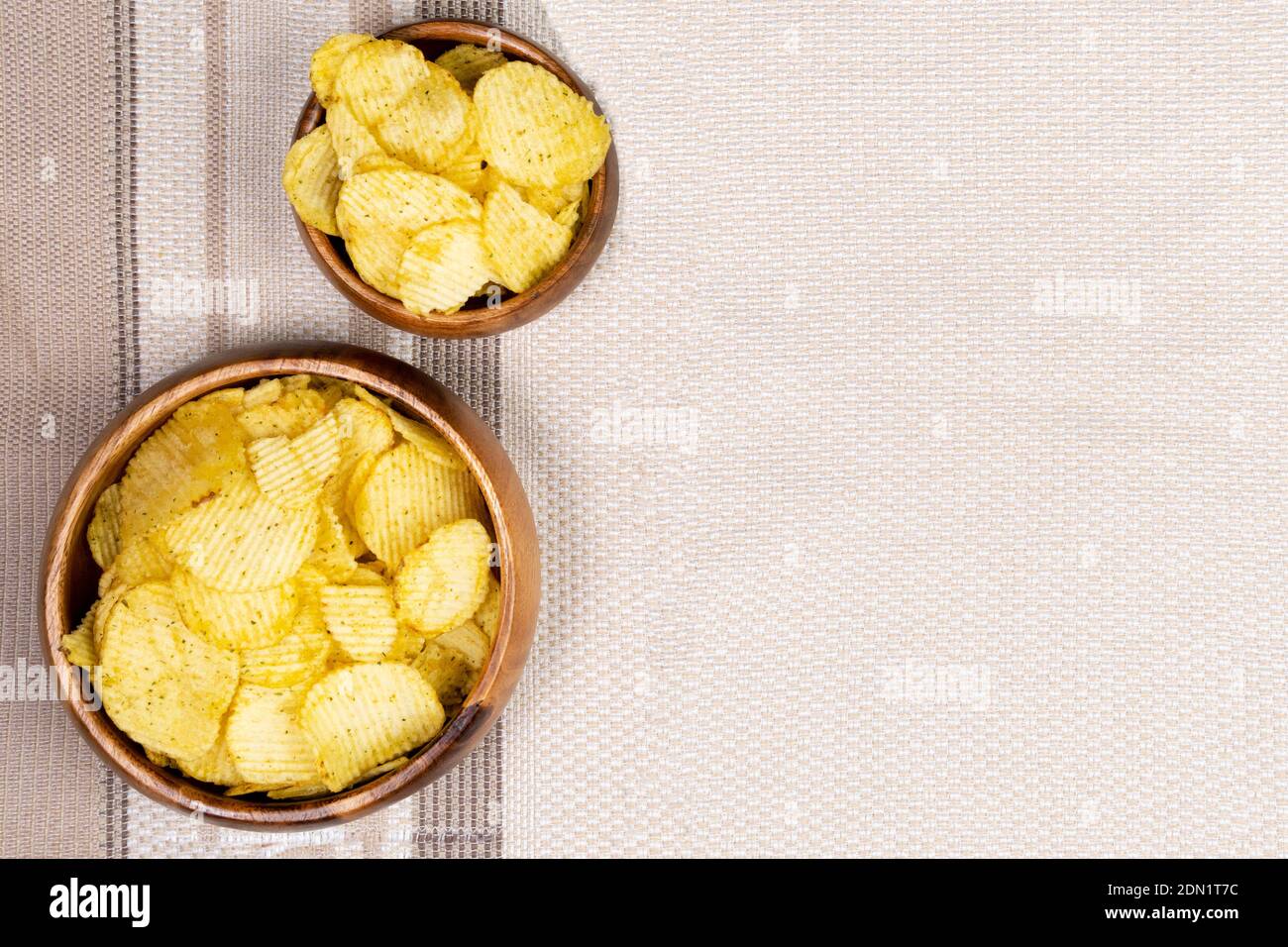 two bowls of potato chips, different portions. top view space for text ...