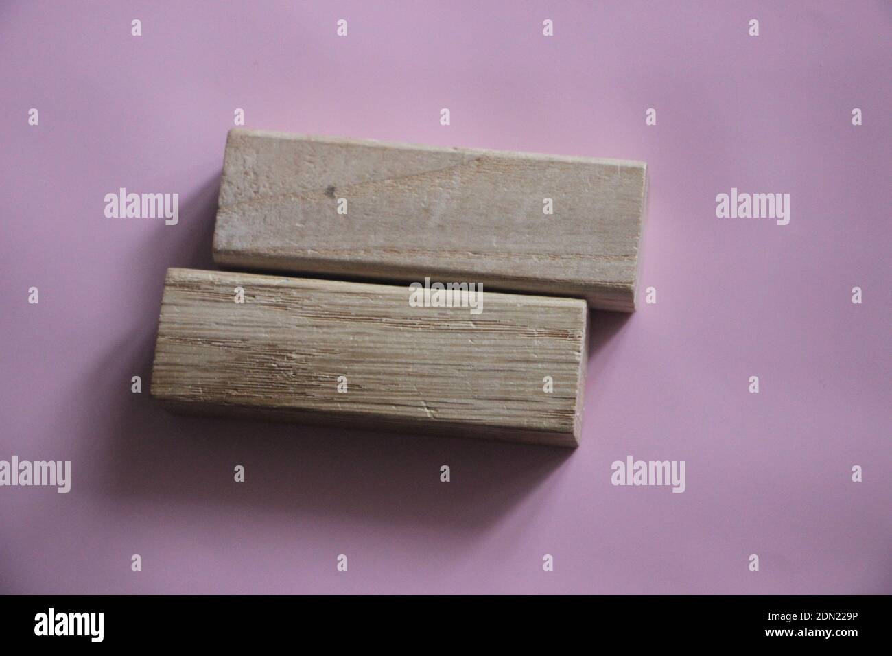 Two wood blocks forming equal sign on soft pink and lilac background ...