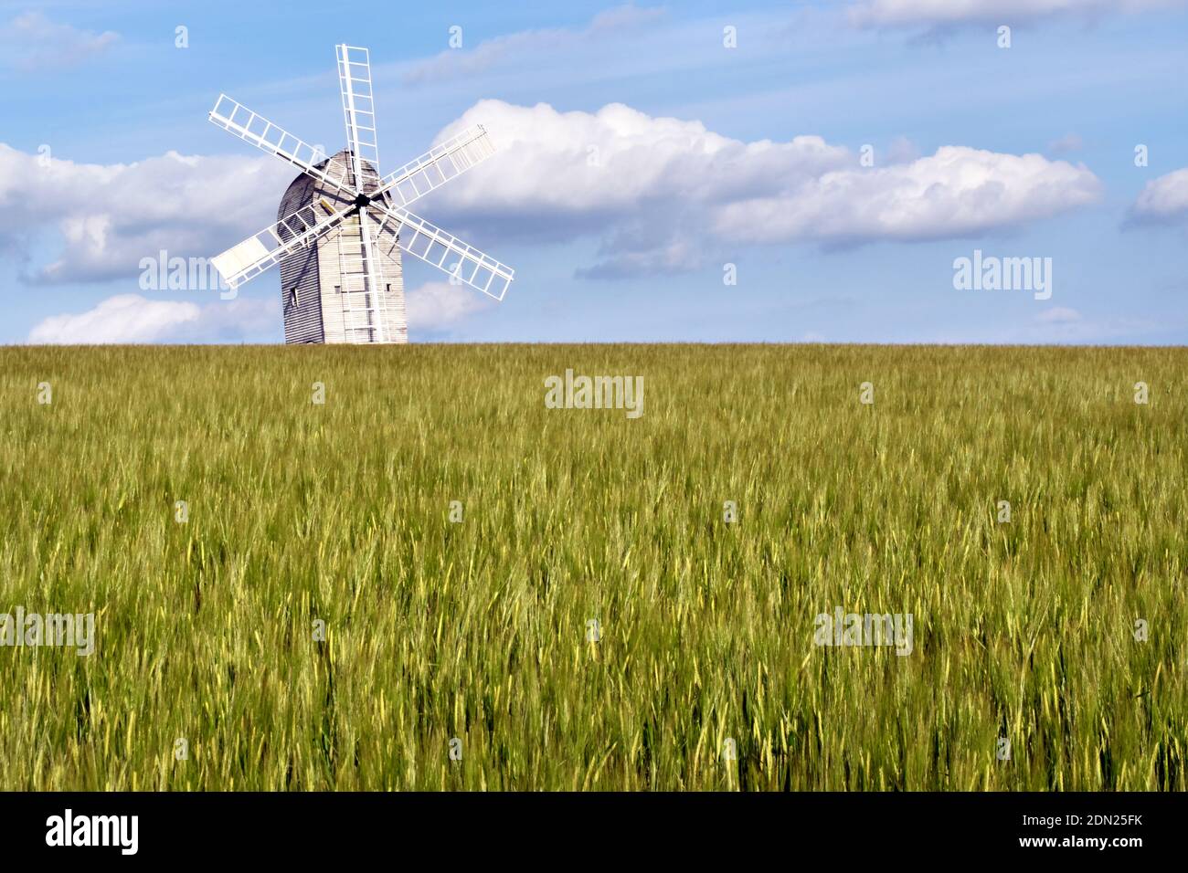 White traditional windmill in green field under a blue sky with white ...