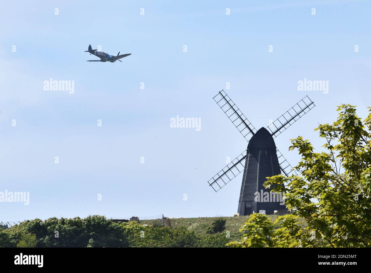 Spitfire flying past windmill Stock Photo - Alamy