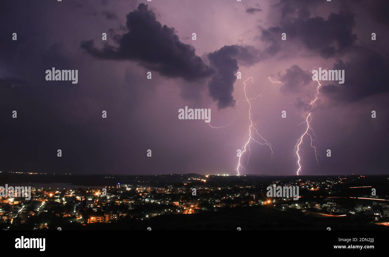 Lightning Over Illuminated Buildings In City At Night Stock Photo - Alamy