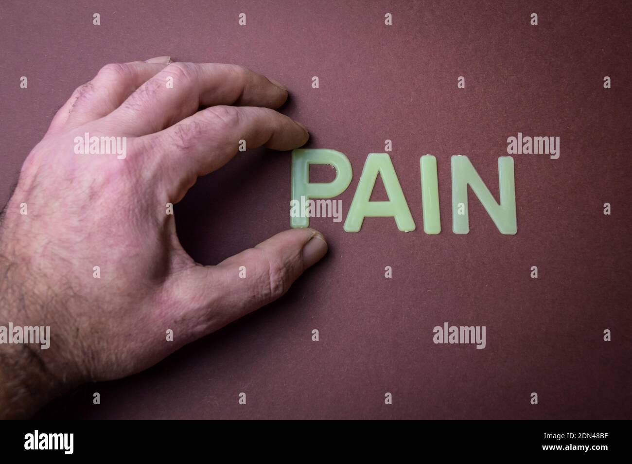 Human fingers holding the word Pain written with plastic letters on ...