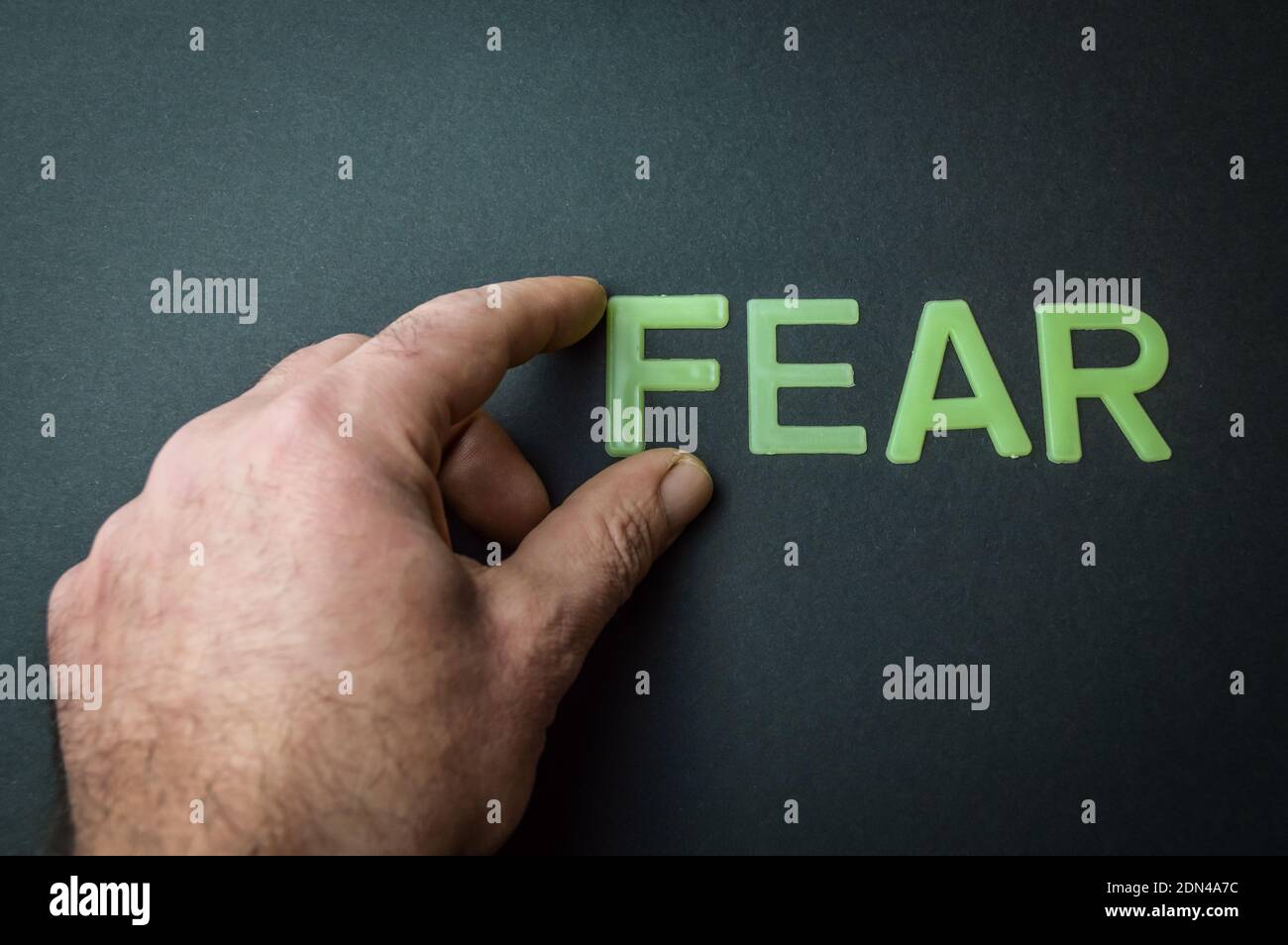 Human fingers removes the word Fear written with plastic letters on ...