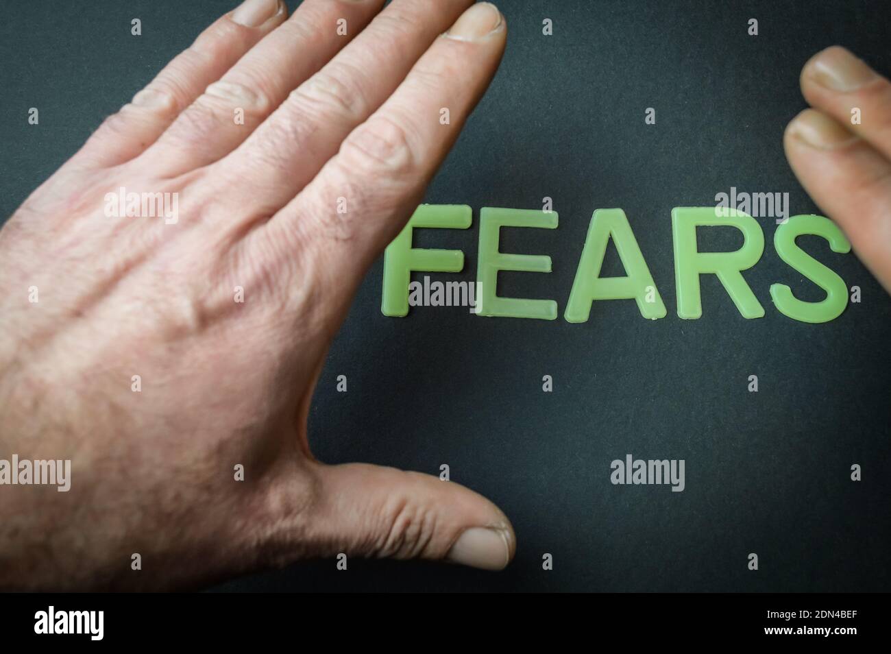 Human hand hides the word Fear written with plastic letters on dark ...