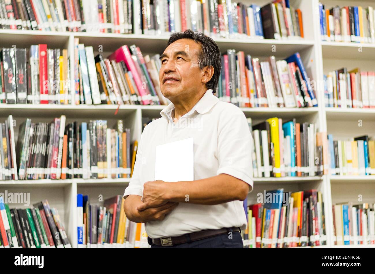 Man Standing Against Bookshelf In Library Stock Photo - Alamy