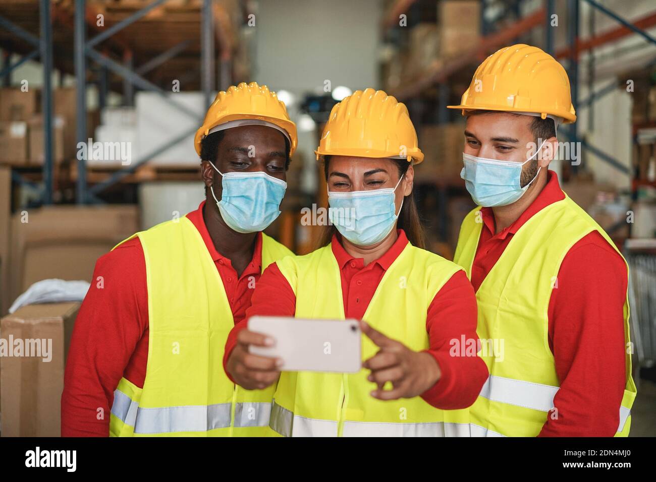 Happy worker taking selfie inside warehouse while wearing safety masks ...