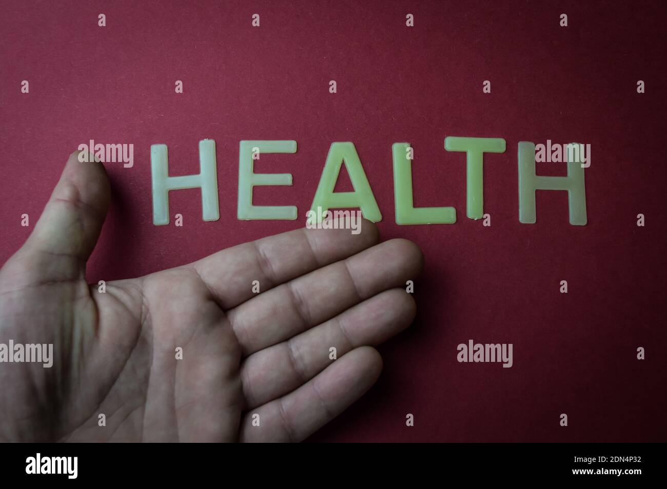 Human hand showing the word Health written with plastic letters on dark ...