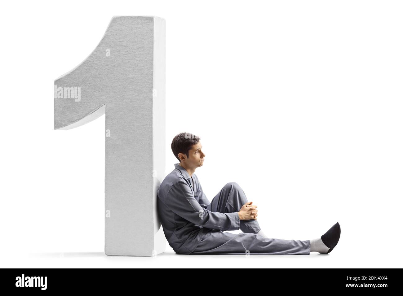 Sad man in pajamas sitting on the floor and leaning on a number one ...