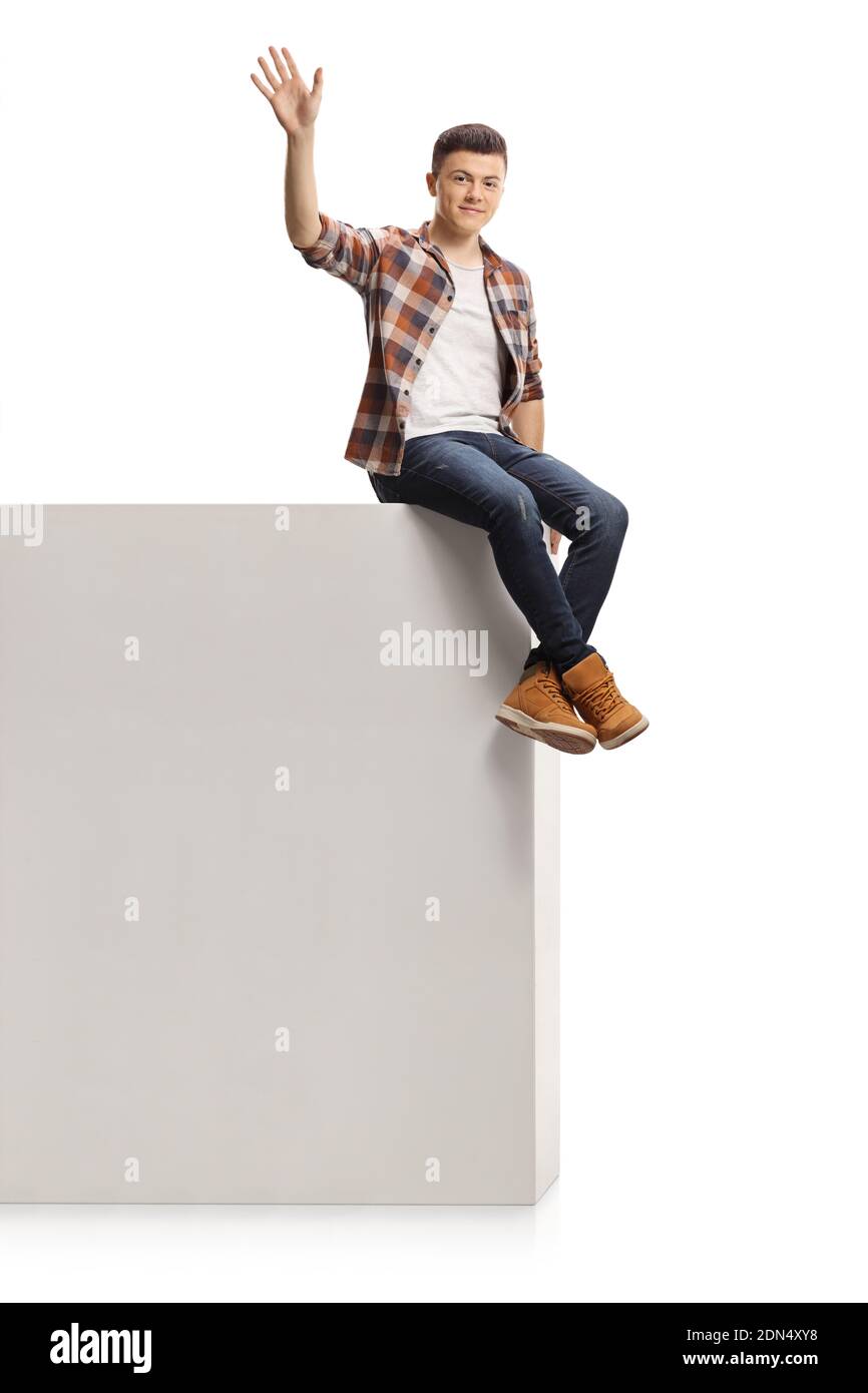 Guy sitting on a wall and waving at camera isolated on white background ...