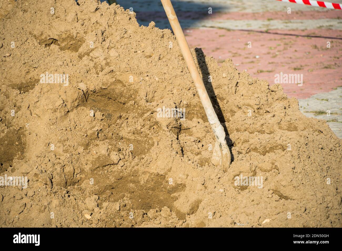 A pile of sand with a shovel stuck in it on a construction site behind ...