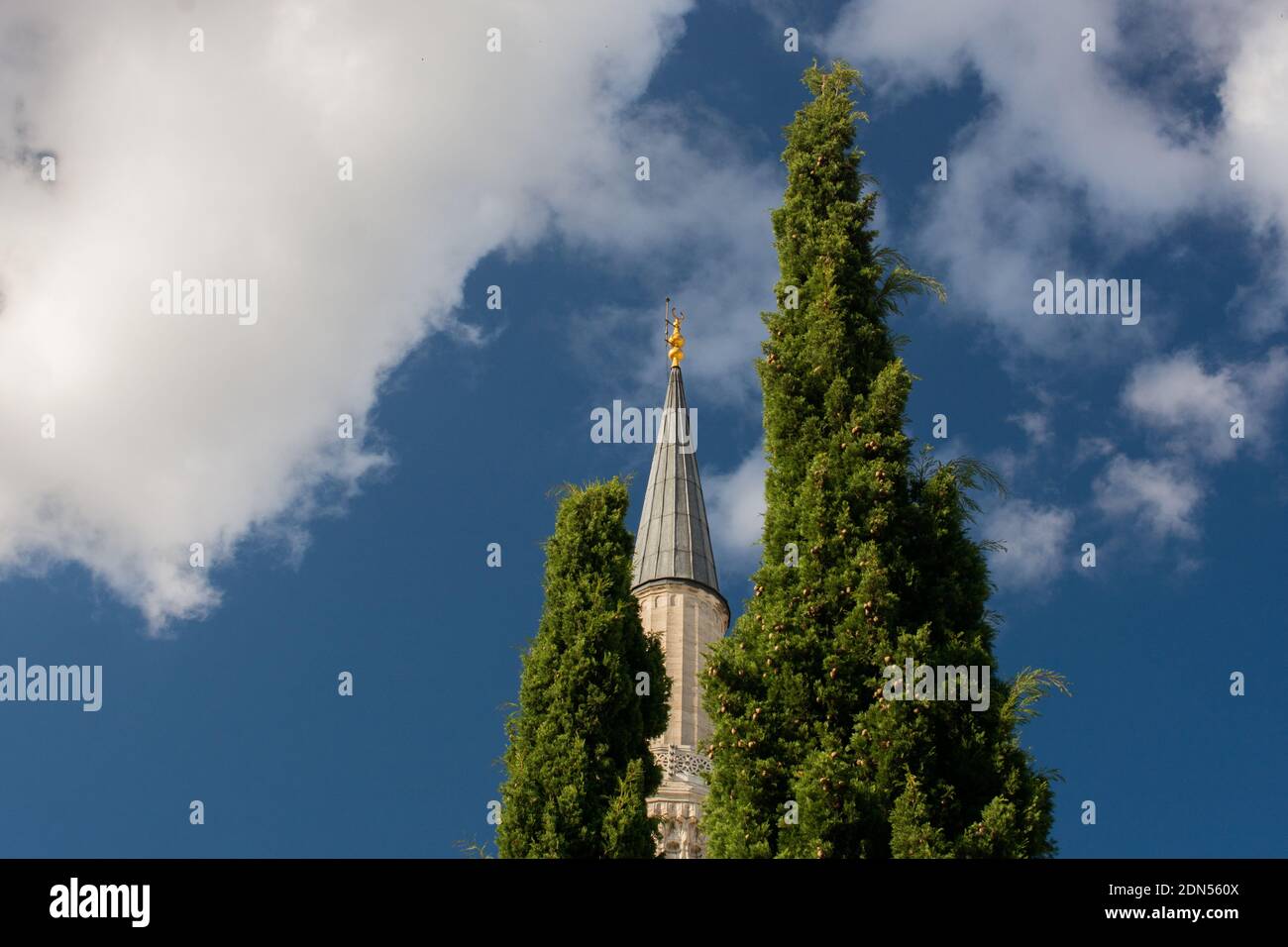 A low angle shot of the minaret of a Muslim mosque surrounded by green ...