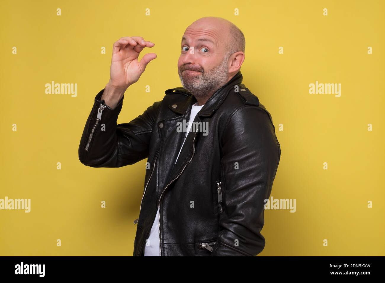 Mature hispanic man gesturing with hand doing small size sign with ...