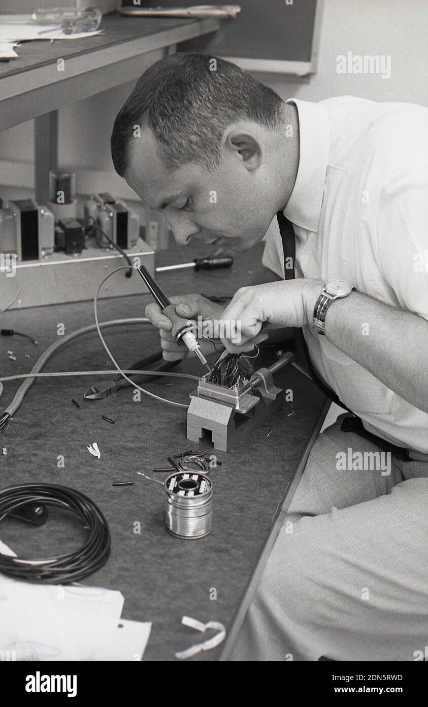 1960s, historical, man using a soldering iron or tool to join wires ...