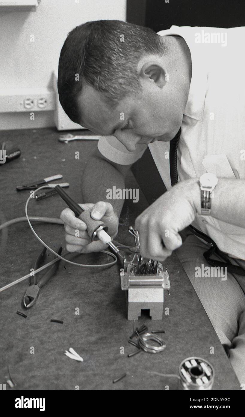 1960s, historical, man using a soldering iron or tool to join wires ...